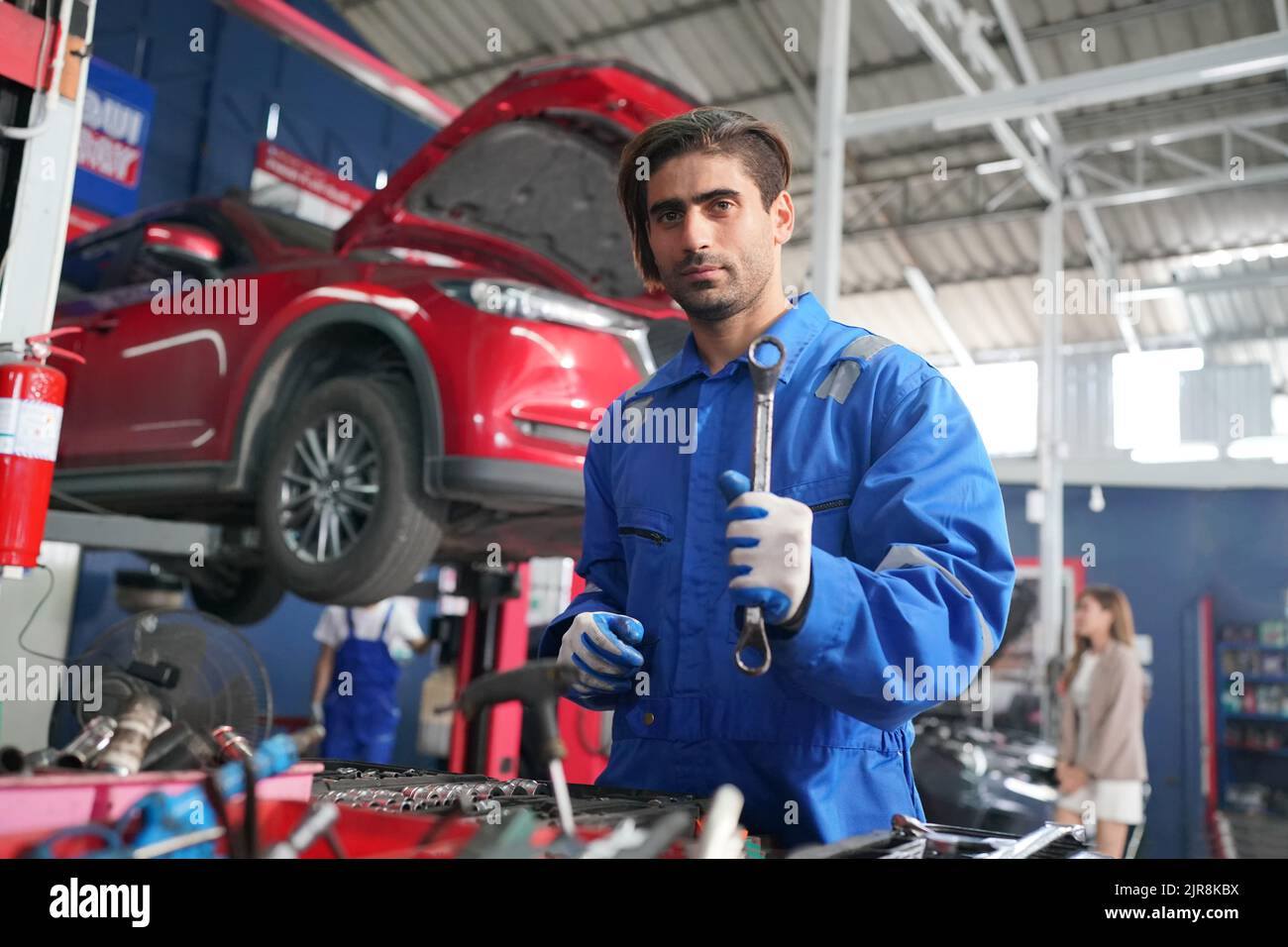 Male car operator wearing blue overalls,cap and gloves working under ...