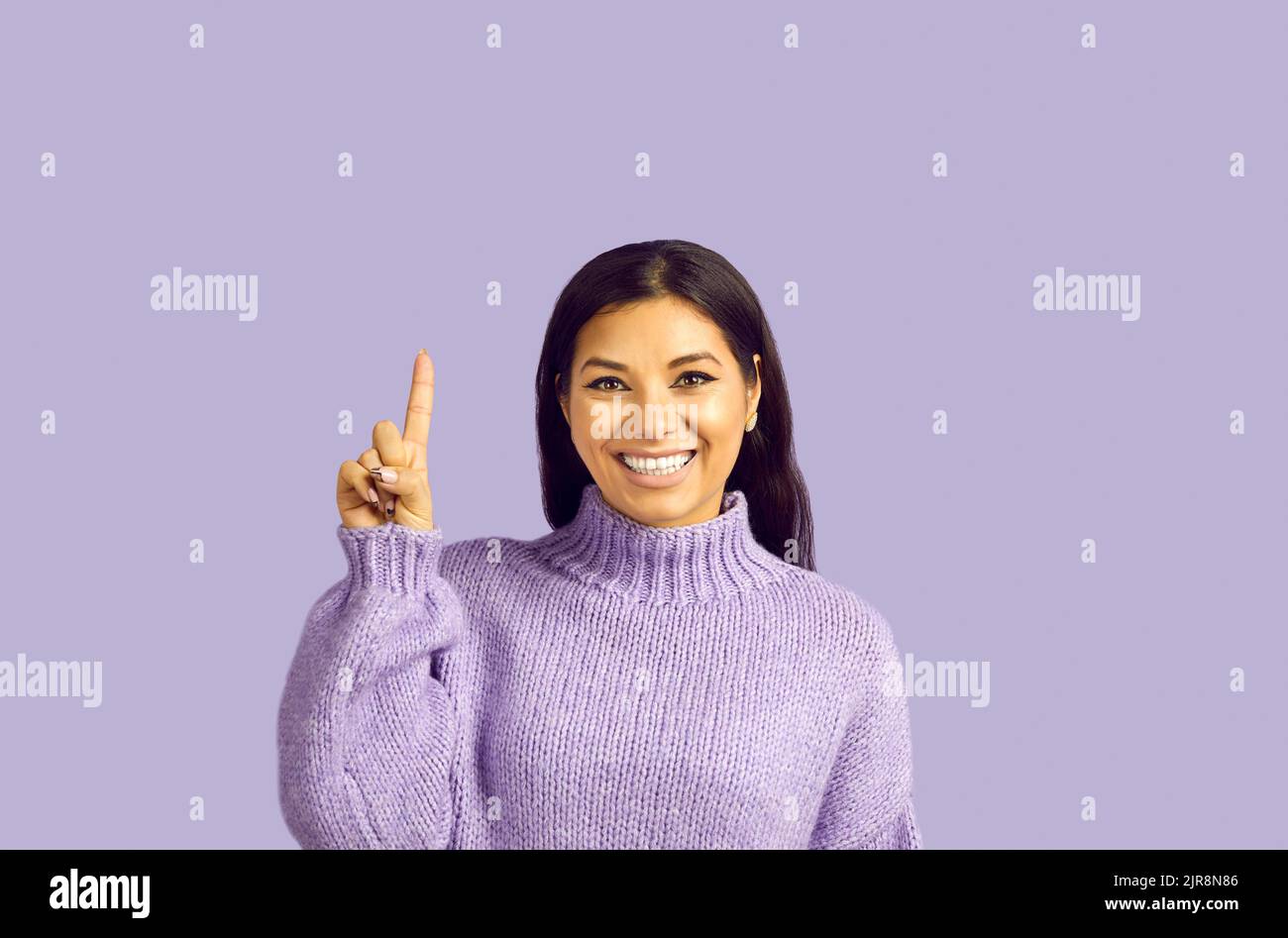 Pretty young female with pleasant smile, makes gesture with index ...