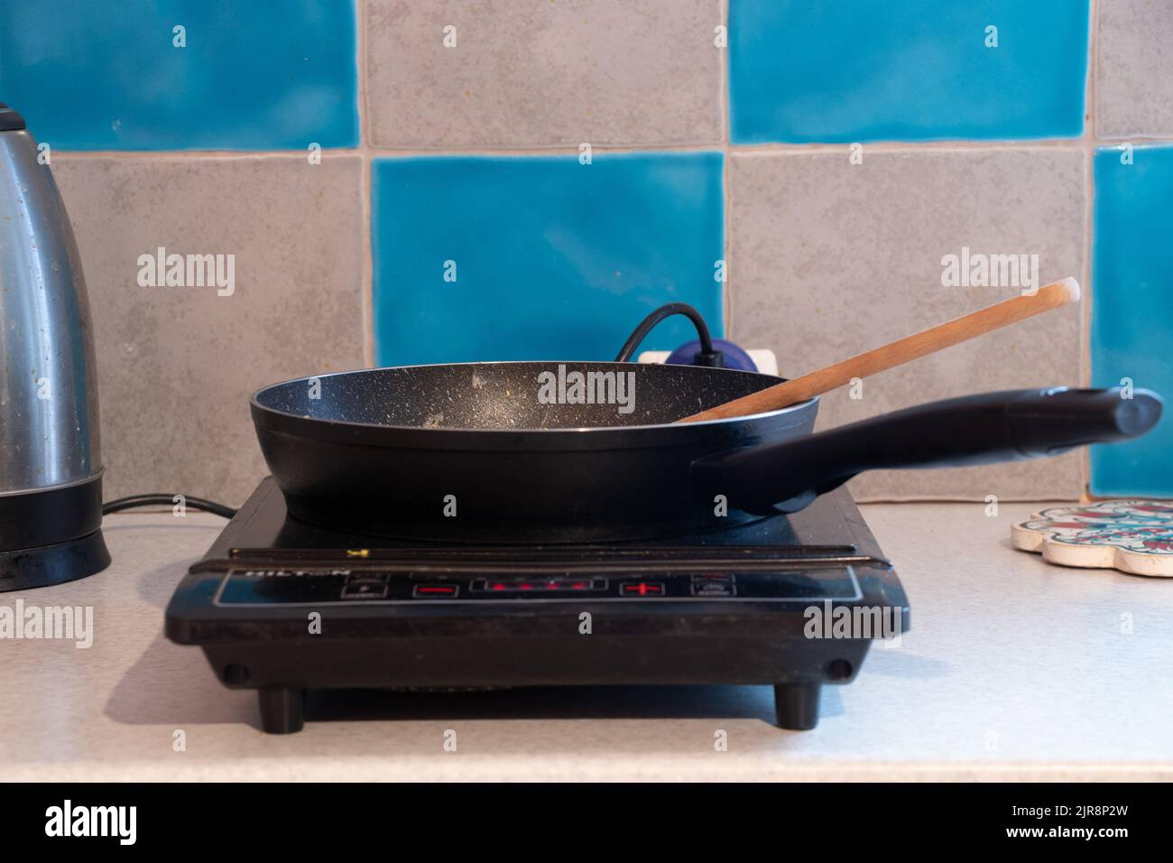 the frying pan is on a single induction electric stove on the kitchen ...