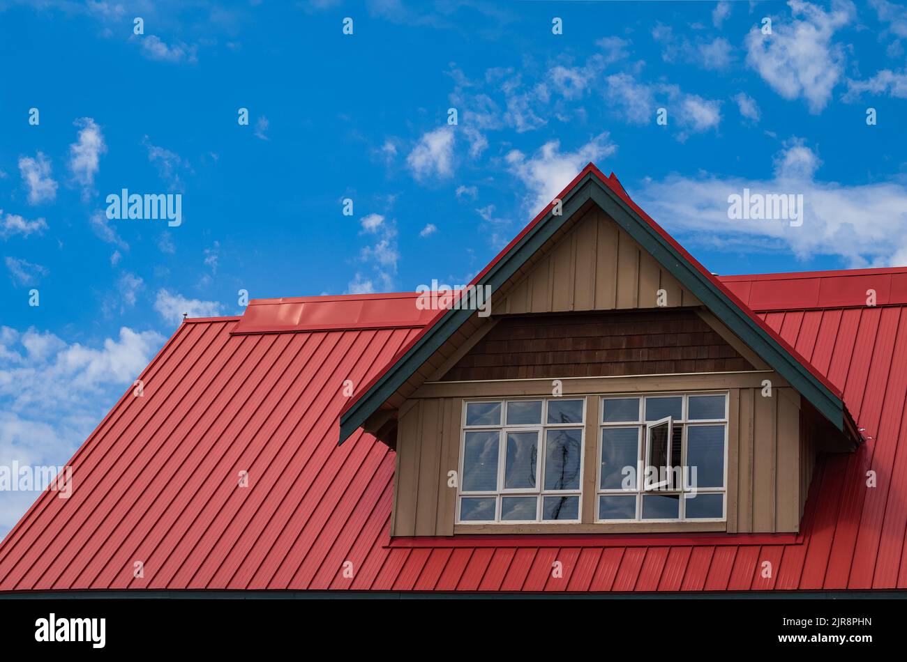 Red roof with dormer in the blue sky background. Decorative metal roof ...