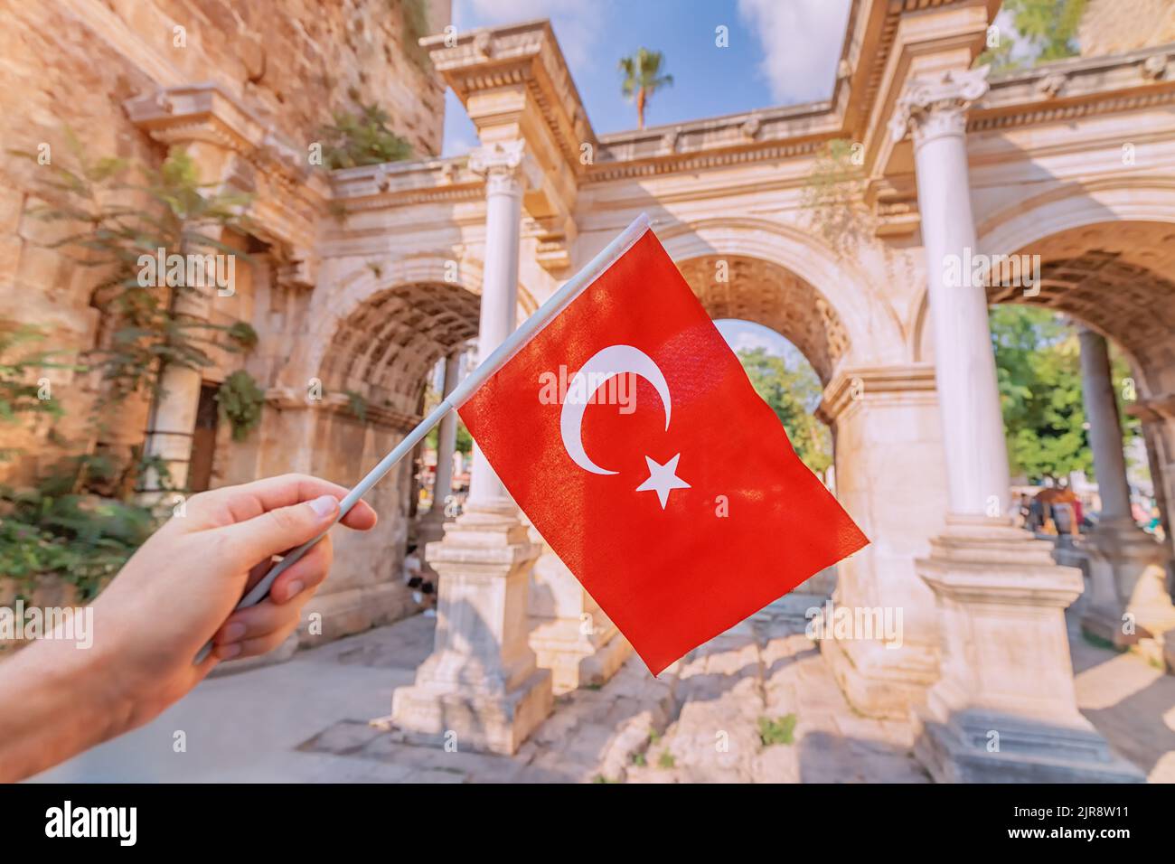 Turkish Flag in hand and famous gate or Hadrian arch in Antalya ...