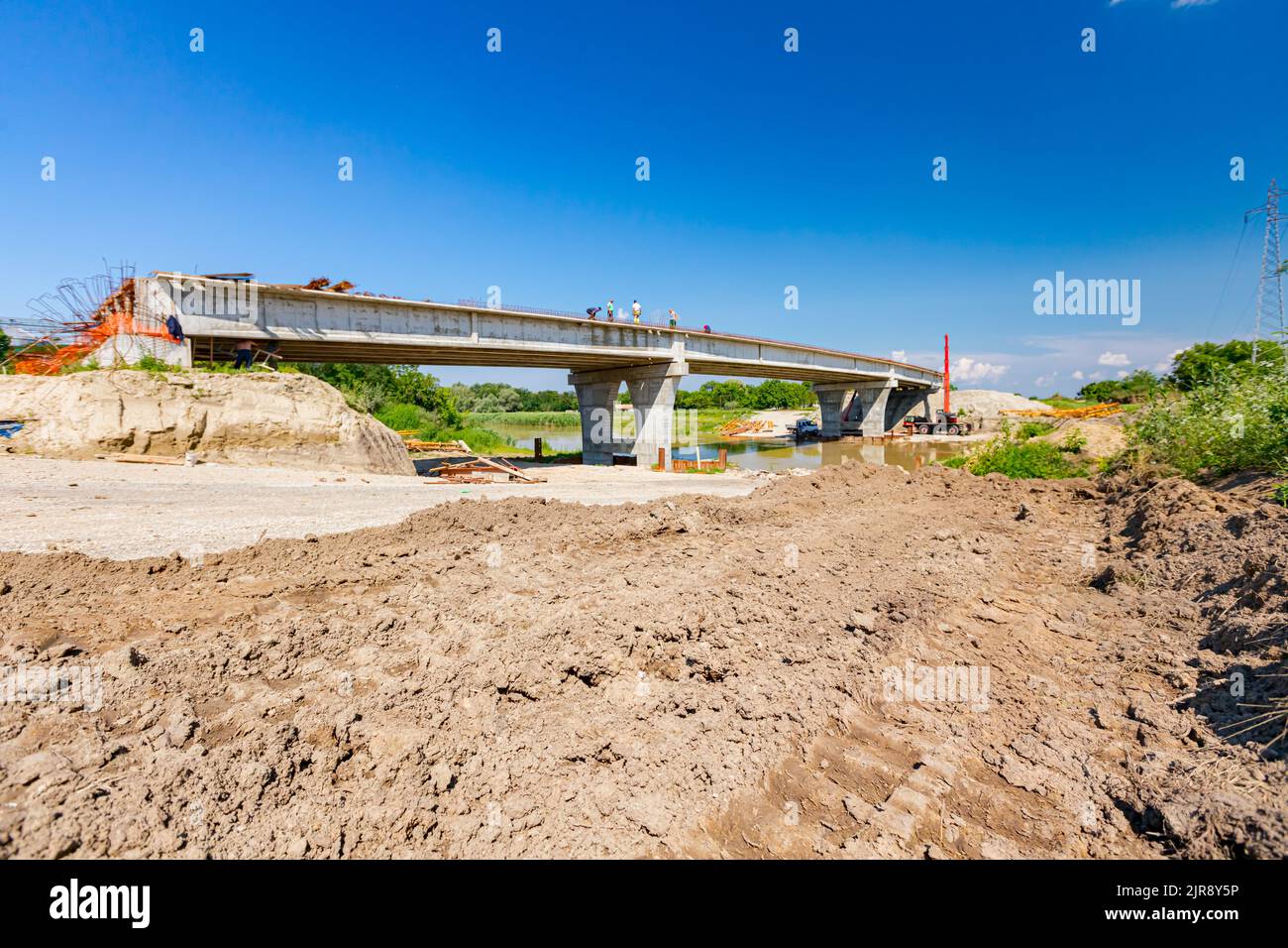 Team of workers are working on the unfinished bridge, road over river ...