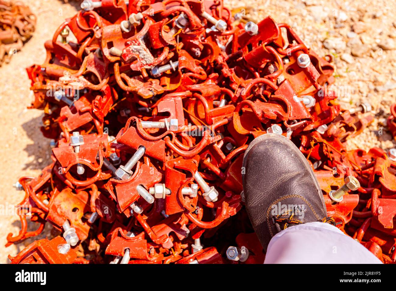 View from above on worker with safety shoe who walks on a pile of parts ...