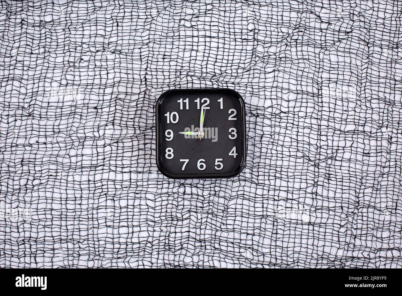 Clock, alarm on a black and white grid background. Time trick. Close up ...