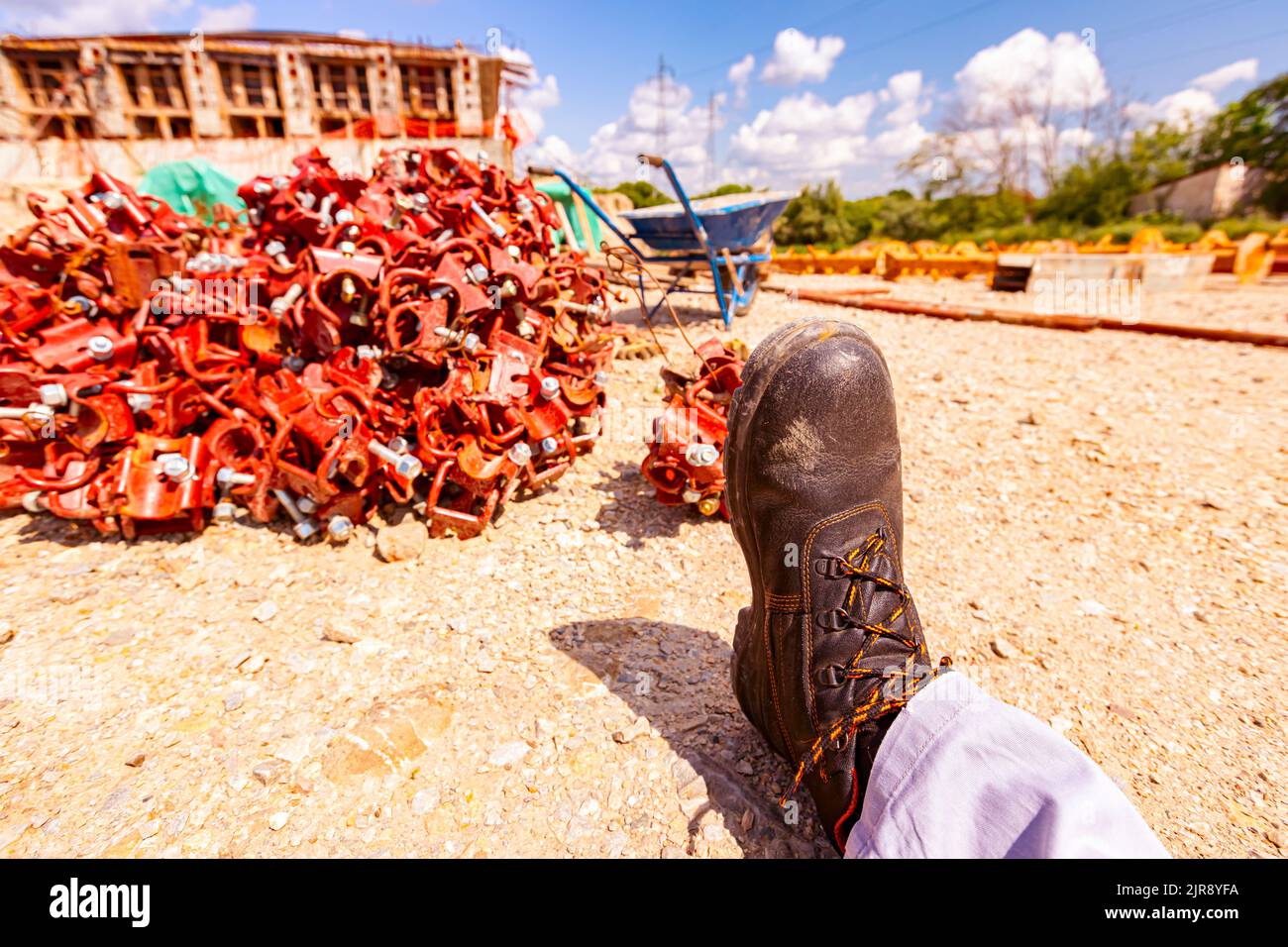 View of a worker's safety shoe on a construction site, a pile of ...
