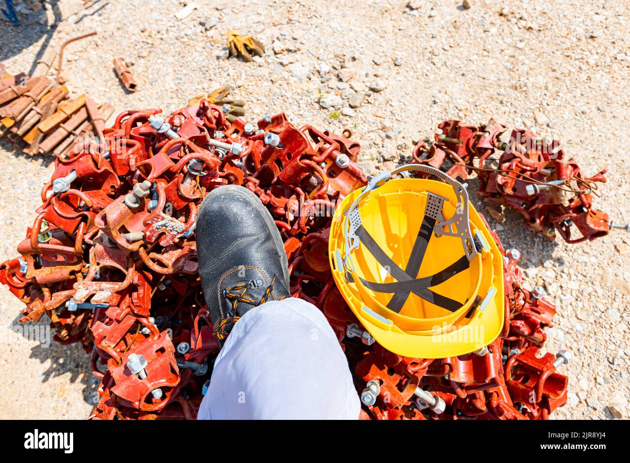 View from above on worker who wears safety shoe and tramples on pile ...