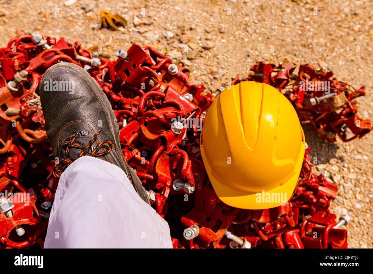 View from above on worker who wears safety shoe and tramples on pile ...