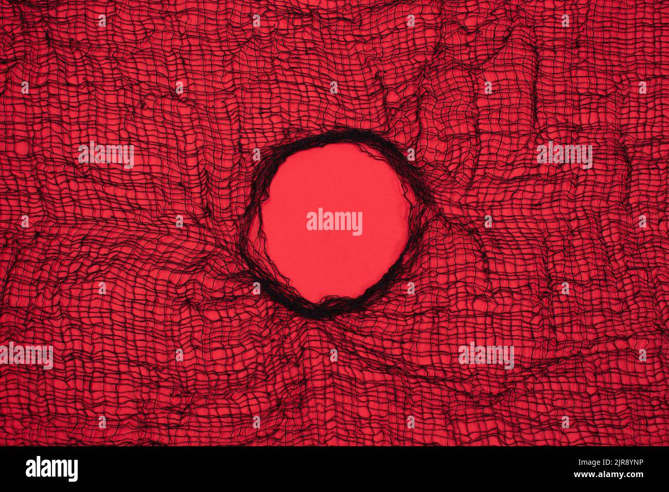 Large Textile mesh hole in the center on red background. Empty space to ...