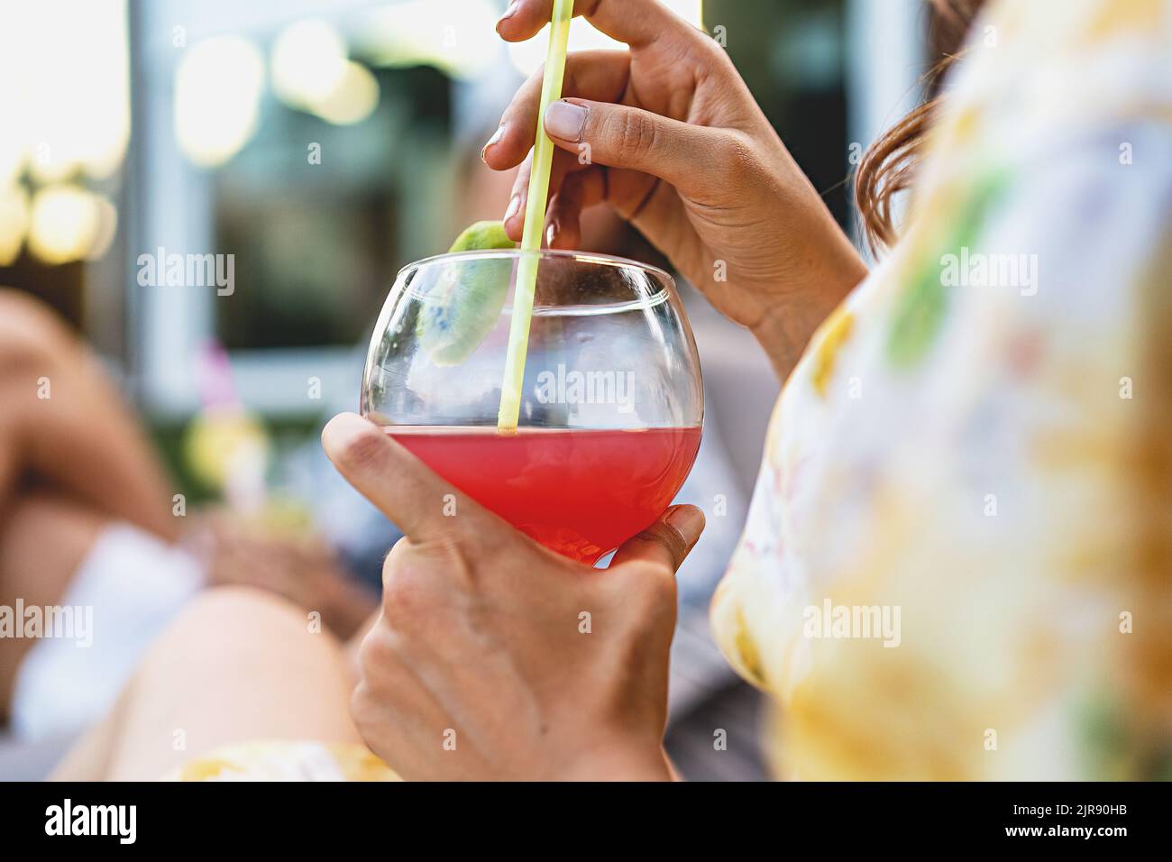 Woman human hand holding an orange spritz cocktail and a drinking straw ...