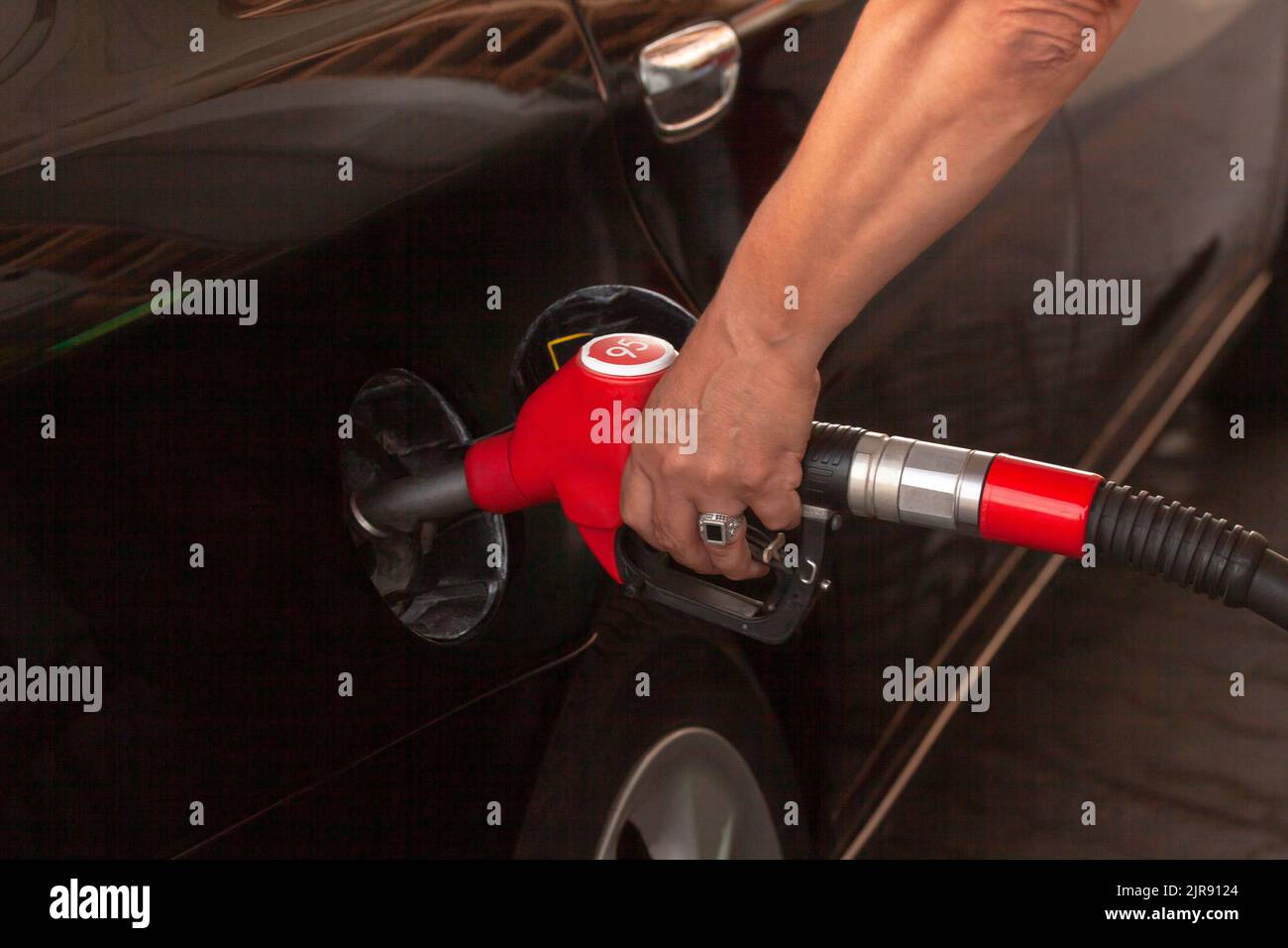 Man's hand is inserting a gas pump nozzle in a fuel tank, Car refueling ...