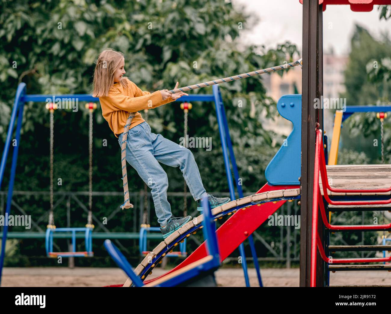 Little girl climbing rope on playground Stock Photo - Alamy