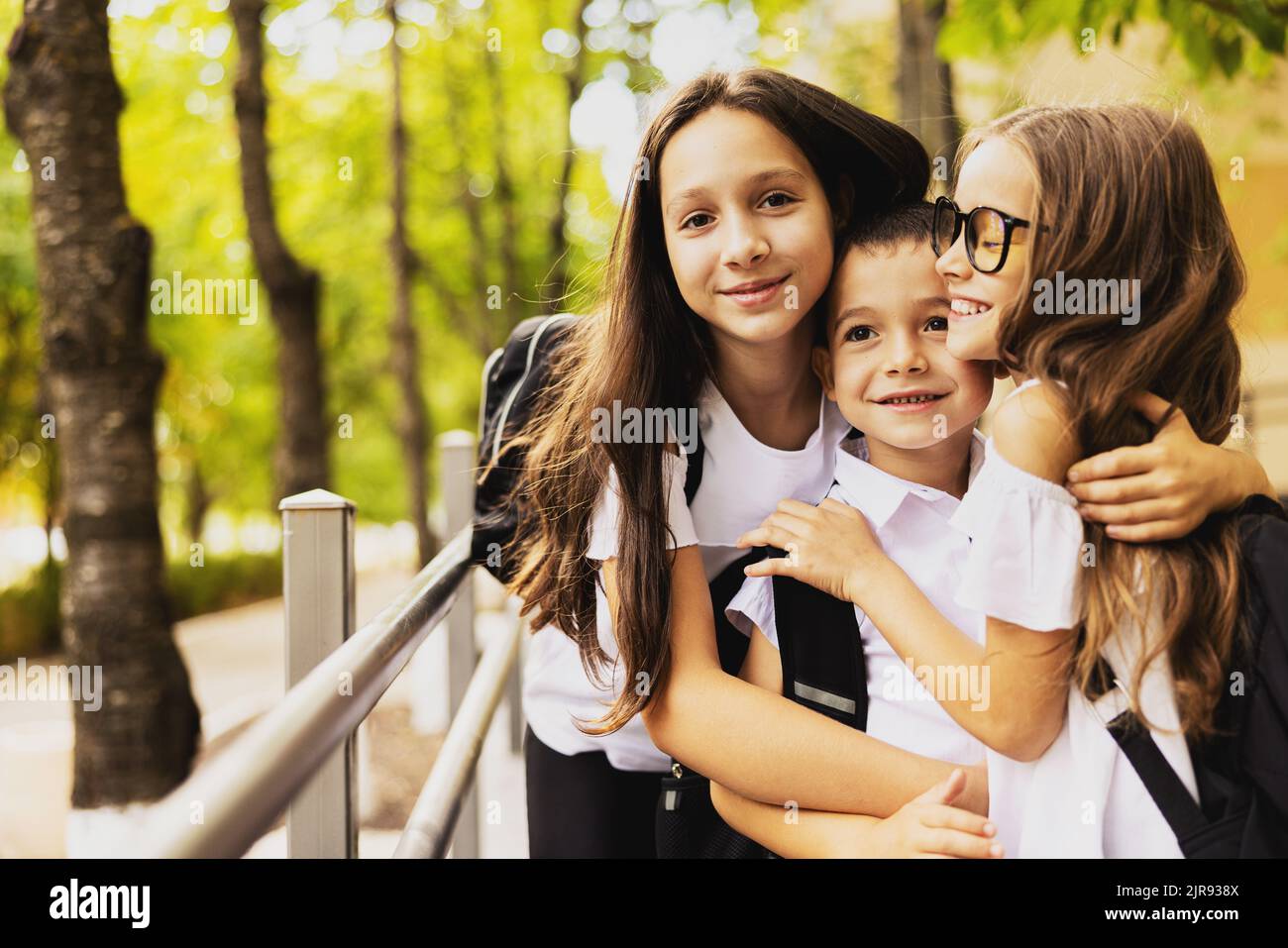 Three brothers hug and are happy on the first day of school. They are ...