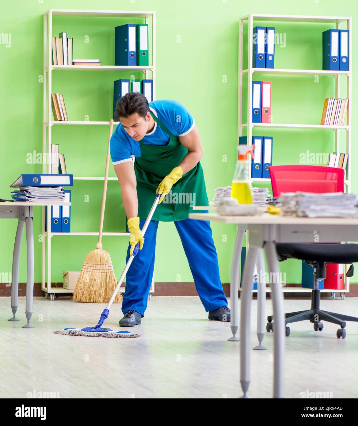 The male handsome professional cleaner doing mopping in the office ...