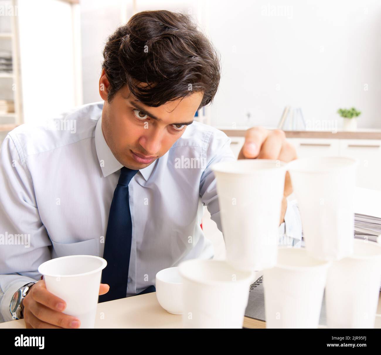 Young employee building pyramid from plastic cups Stock Photo - Alamy