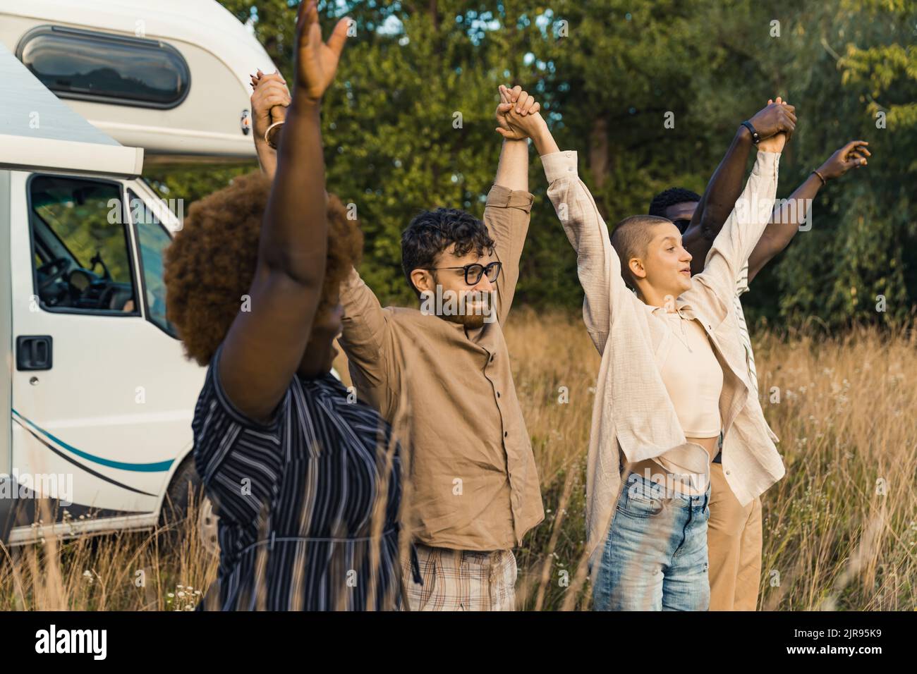 Group of happy young best friends raising and holding each others hands ...