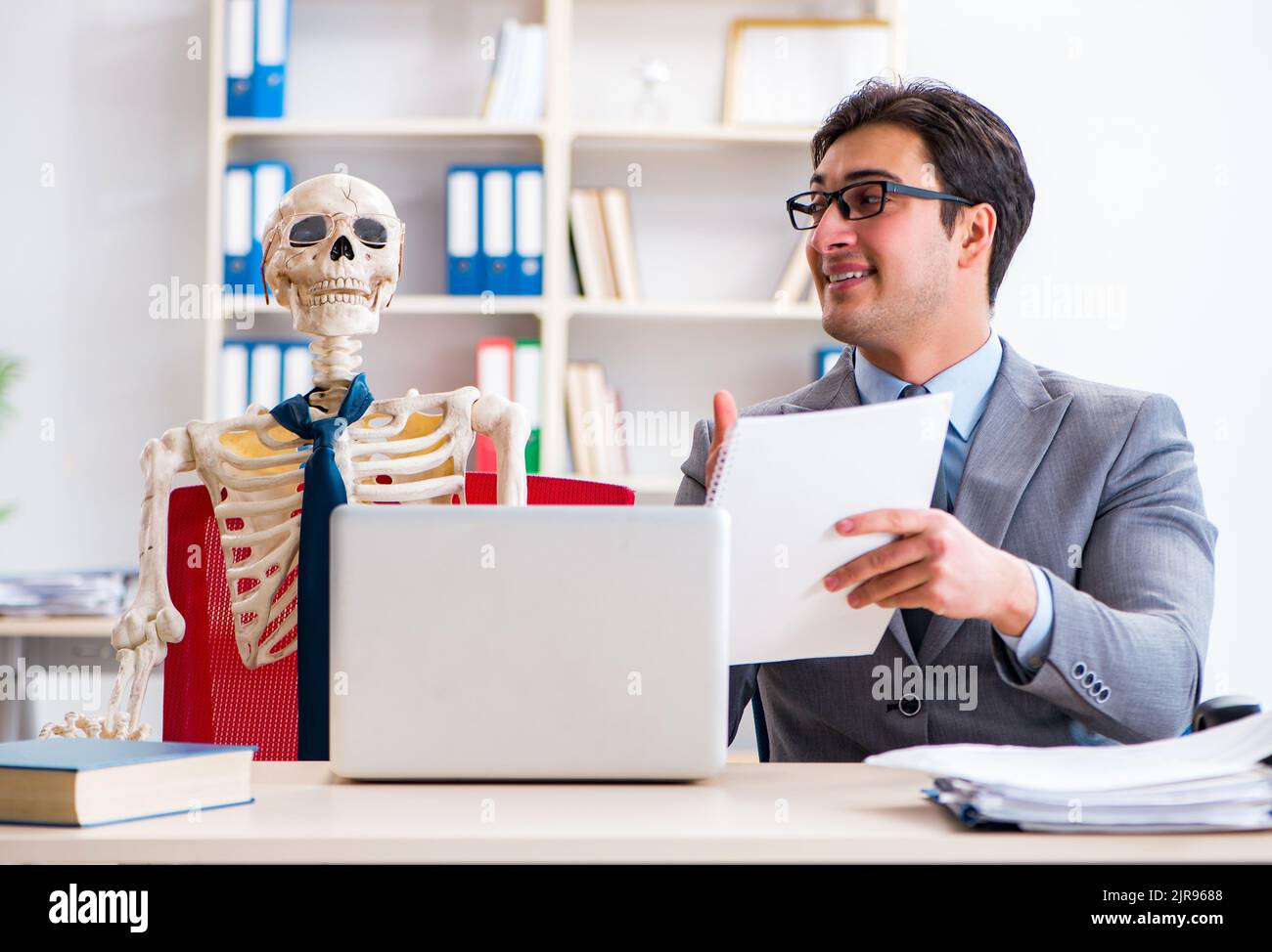 The businessman working with skeleton in office Stock Photo - Alamy