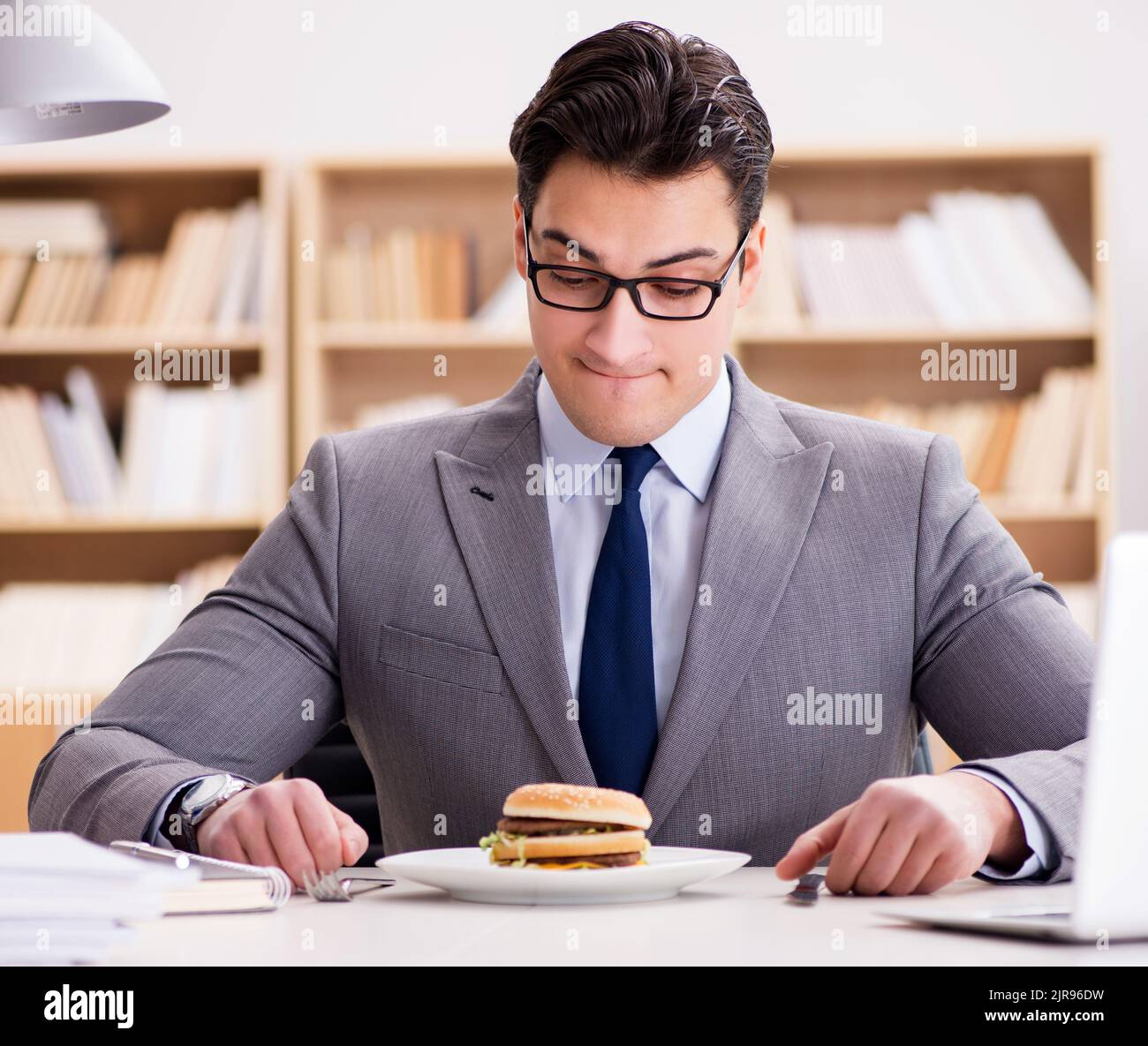The hungry funny businessman eating junk food sandwich Stock Photo - Alamy