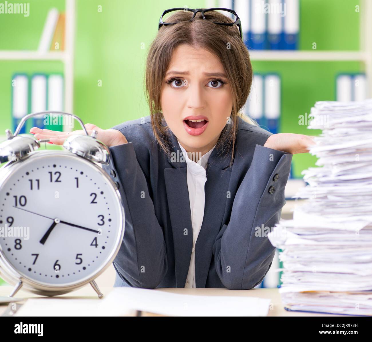 Young female employee very busy with ongoing paperwork in time ...
