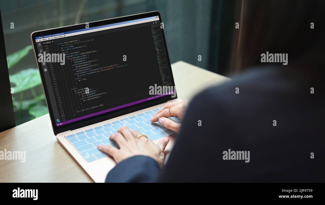 Over shoulder view of female software developer working on web site project, programming on ...
