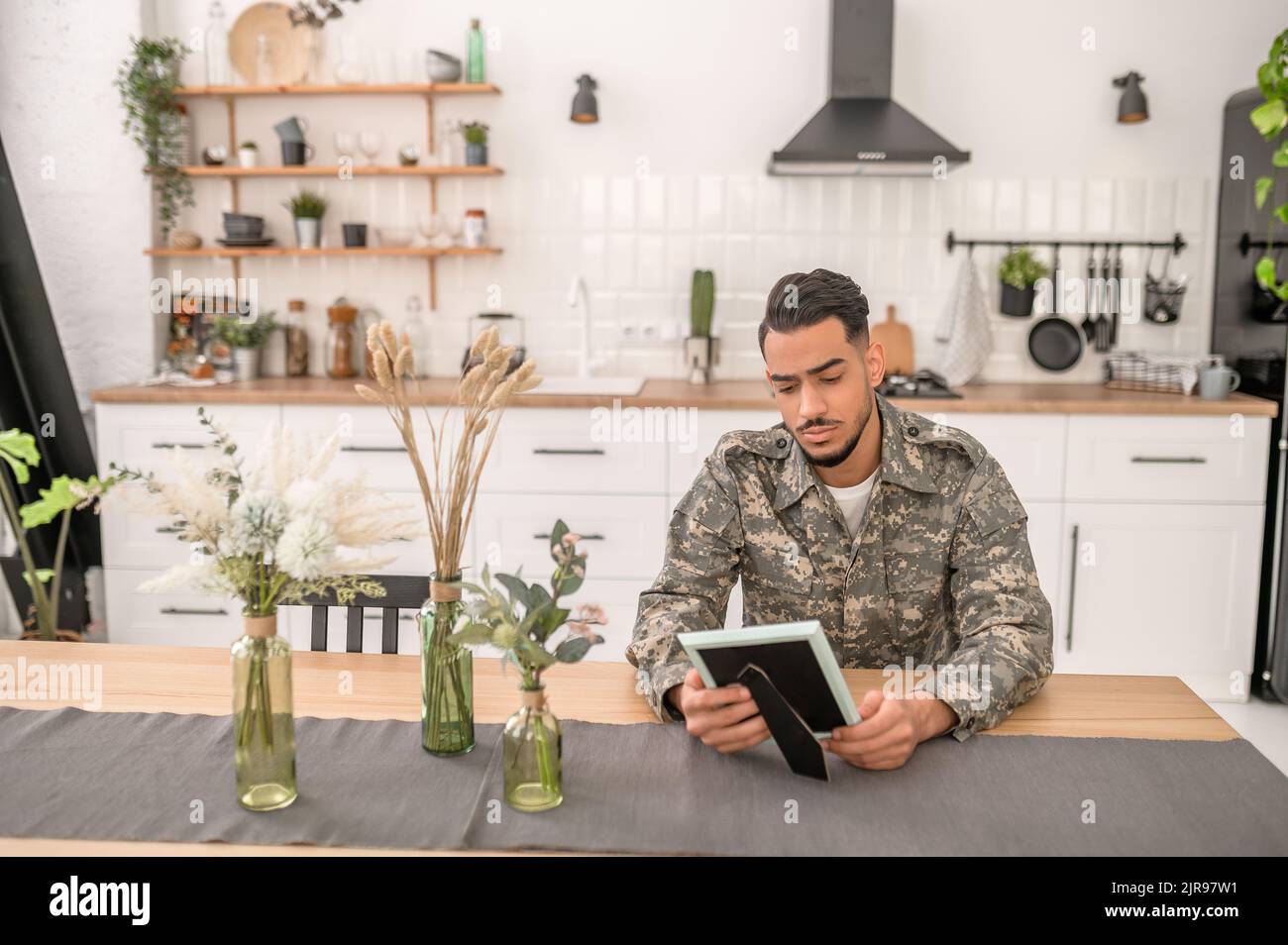 Dispirited serviceman staring at the photo in his hands Stock Photo - Alamy