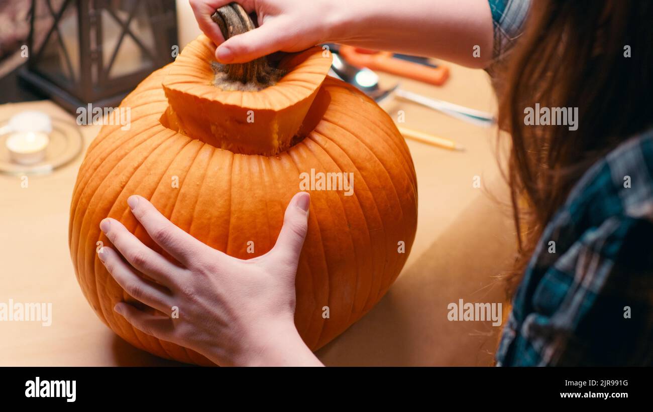 Preparing pumpkin for Halloween. Taking out lid and seeds. Woman ...