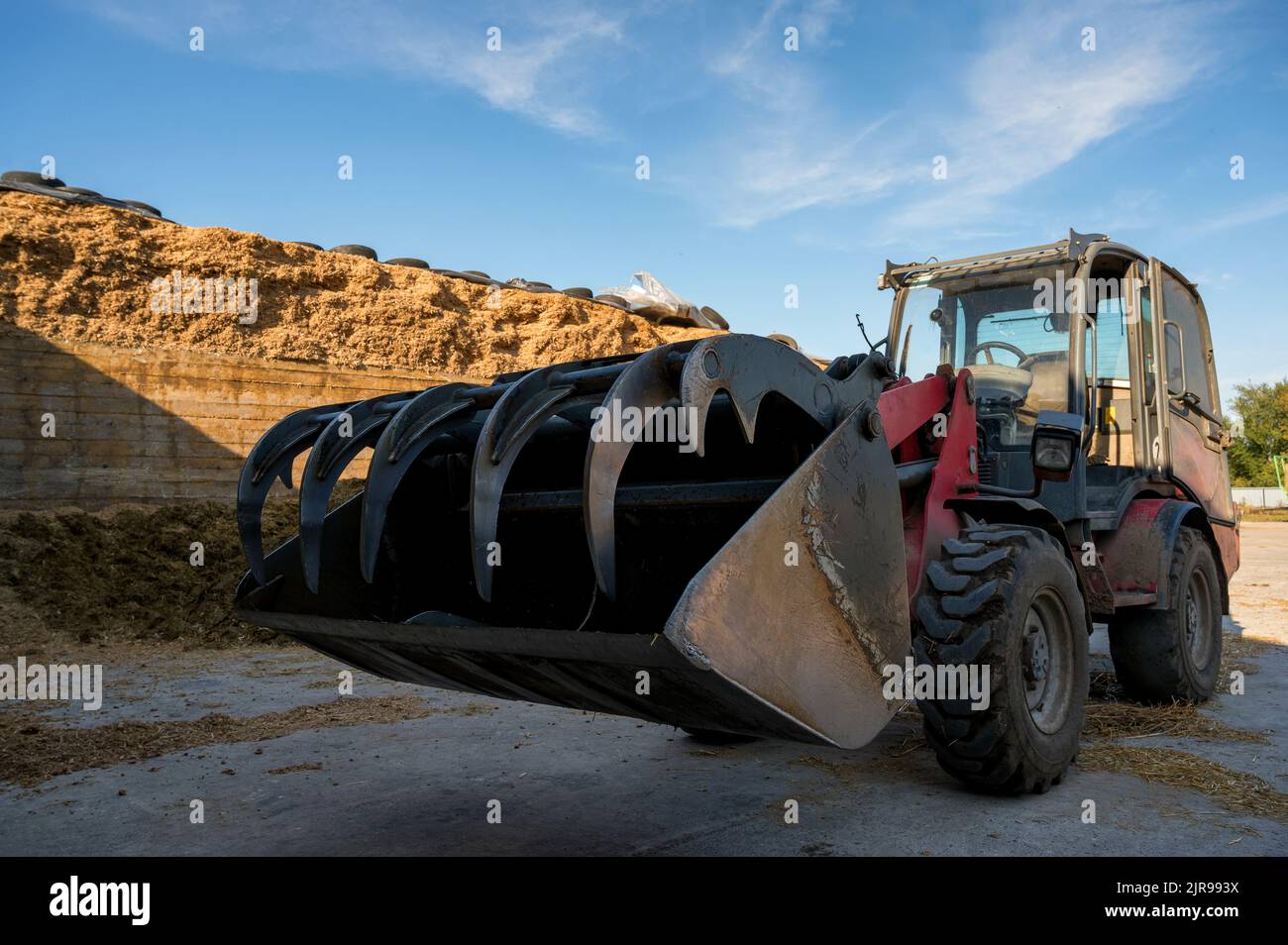 Farmer unloading round bales of straw with a front end loader Storing ...