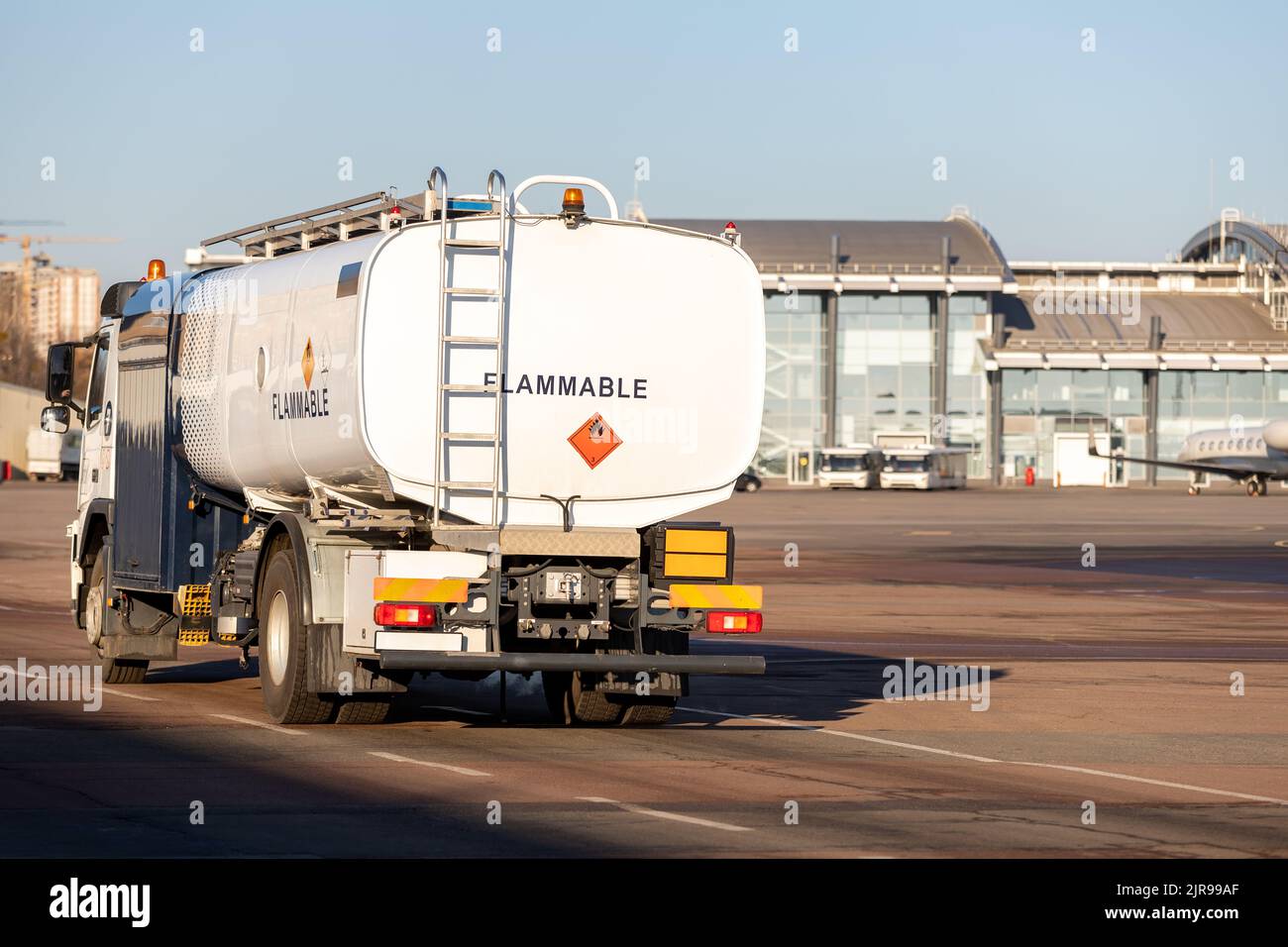 Back view small modern fuel tanker truck driving on airfield taxiway ...