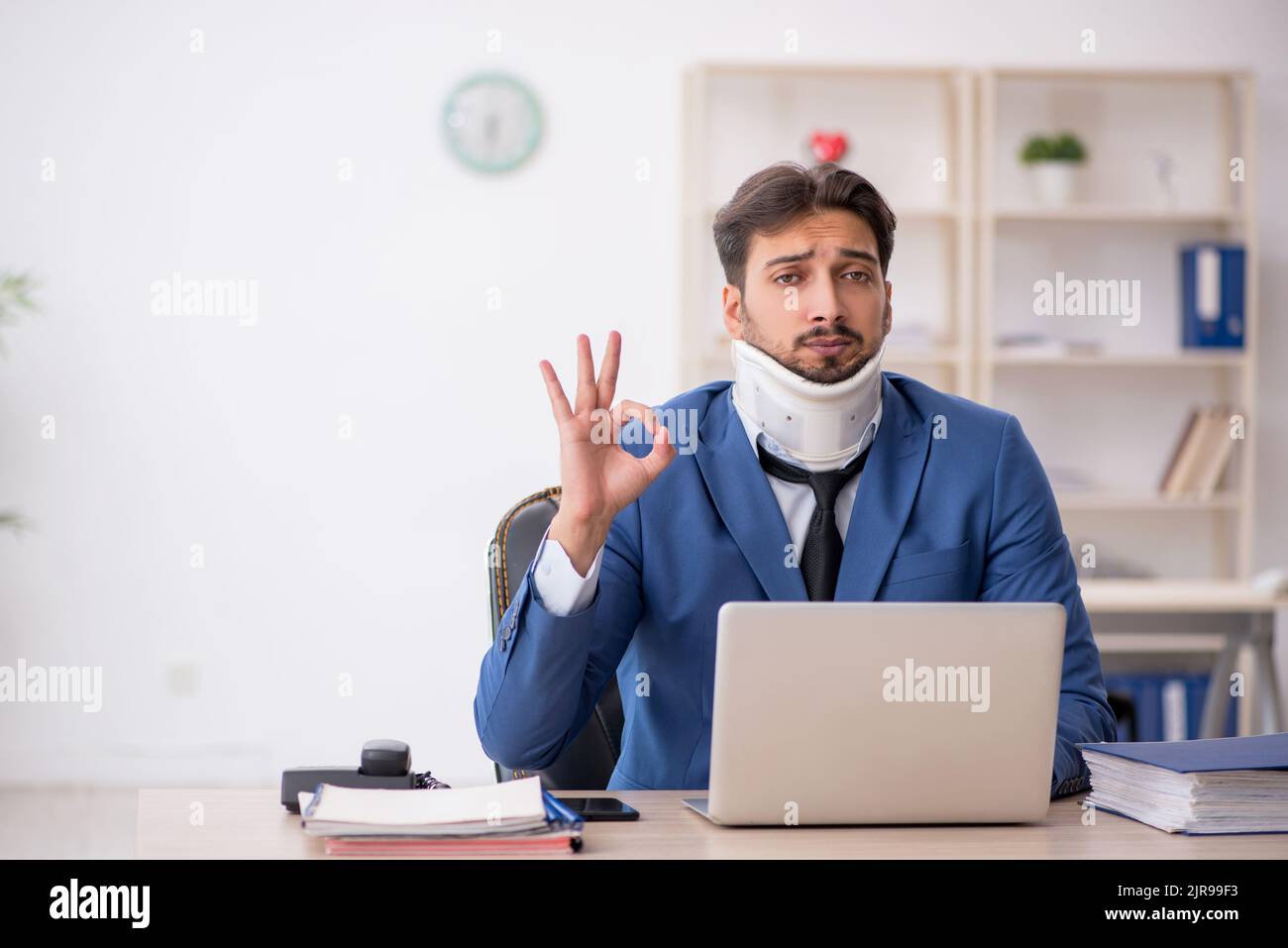 Young neck injured businessman employee at workplace Stock Photo - Alamy