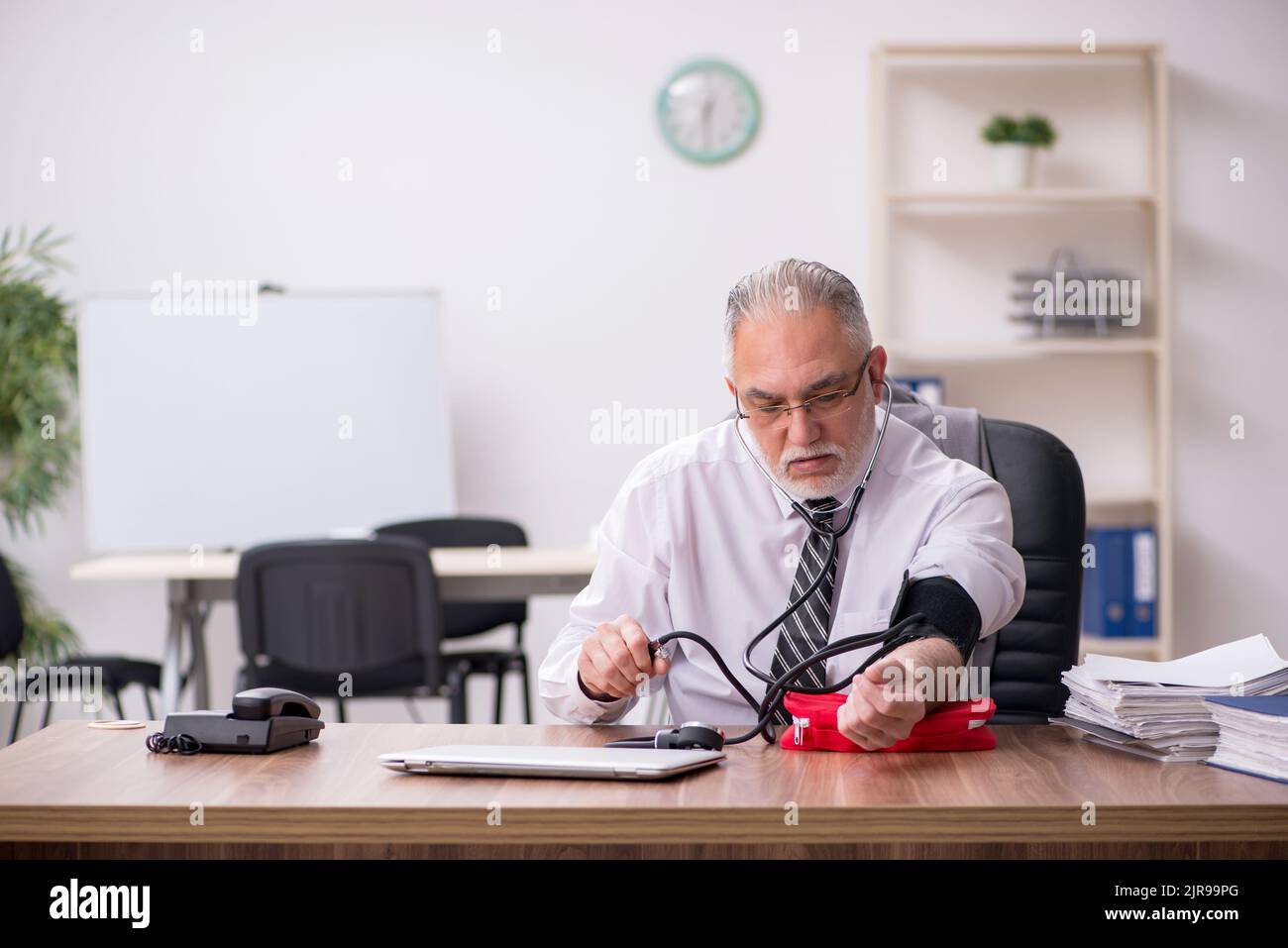 Aged male employee feeling bad in the office Stock Photo - Alamy