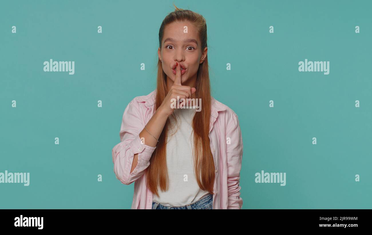 Shh be quiet please. Pretty teenager scared girl presses index finger ...