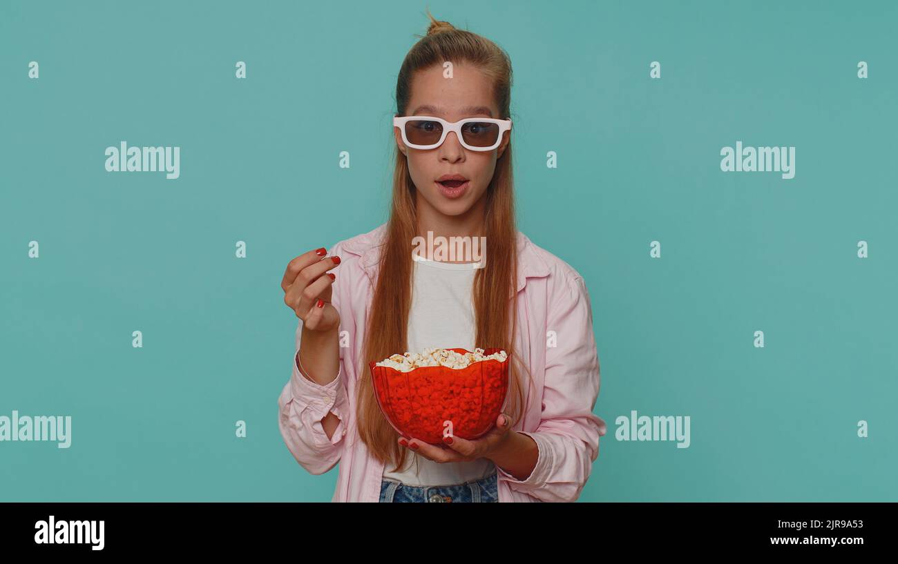Excited teenager girl eating popcorn and watching interesting tv serial ...