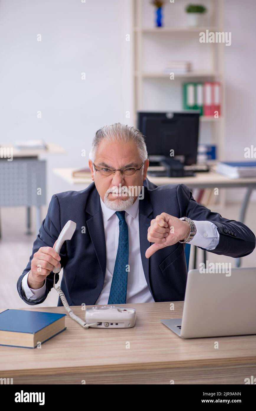 Old businessman employee speaking on the phone in the office Stock ...