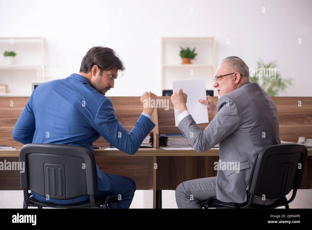 Two male employees working at workplace Stock Photo - Alamy