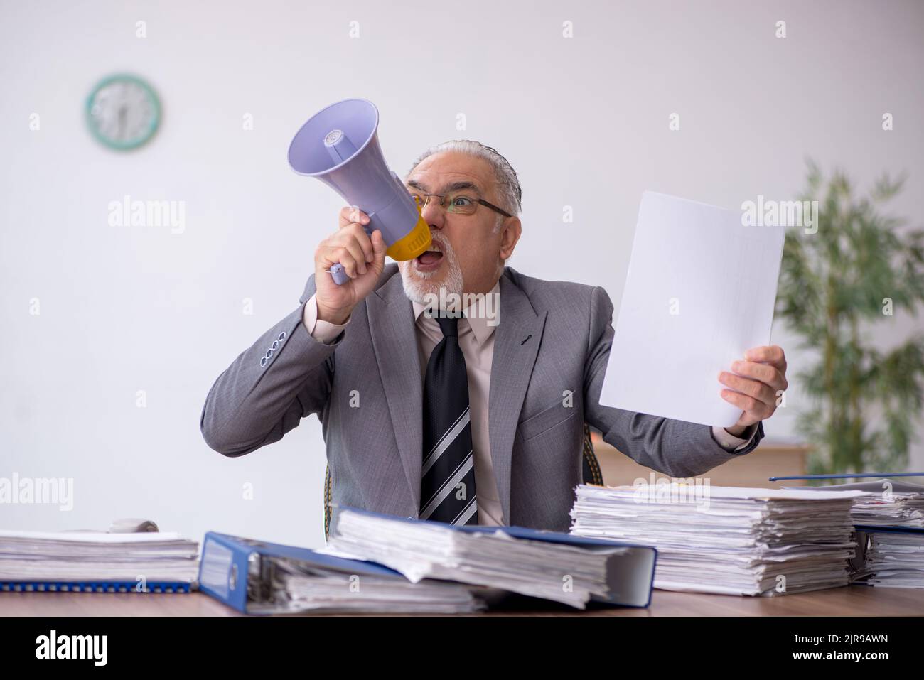Old male boss holding megaphone at workplace Stock Photo - Alamy