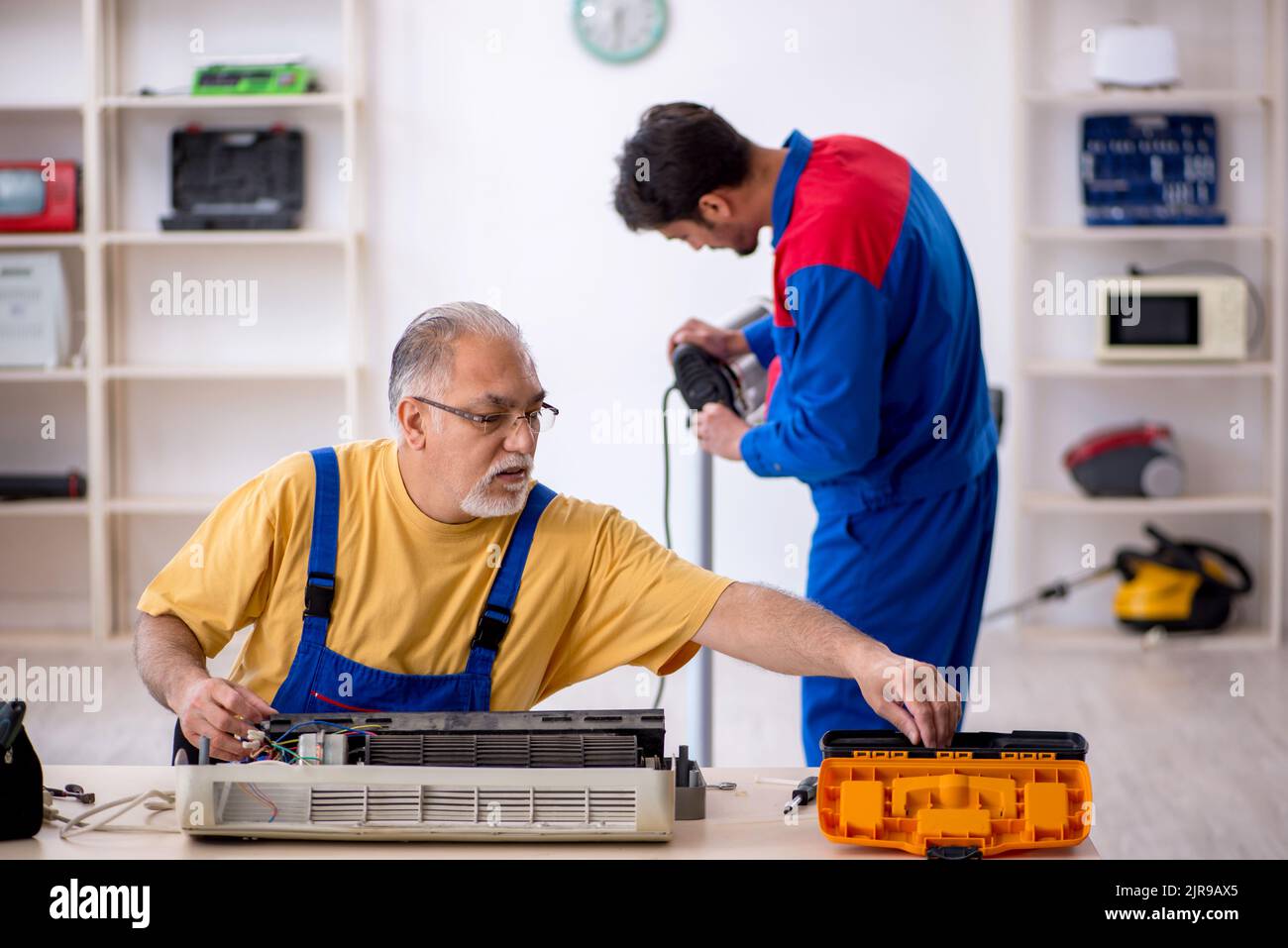 Two repairmen repairing air-conditioner at workshop Stock Photo - Alamy