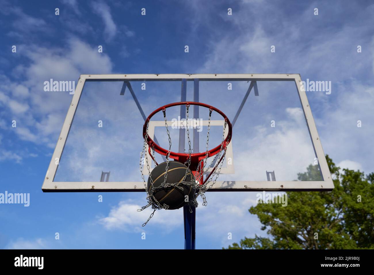 Street basketball ball falling into the hoop. Close up of black ball in ...