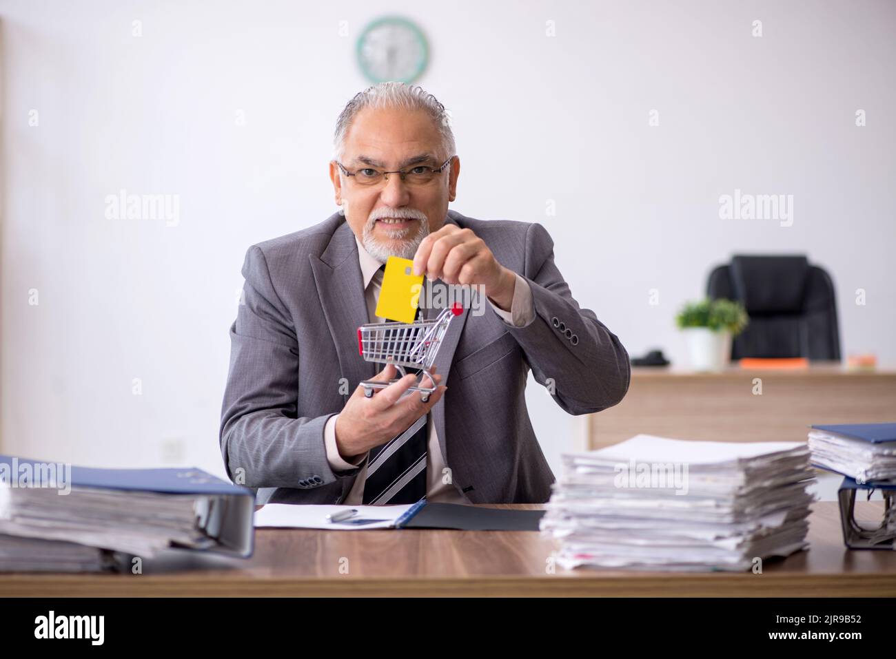 Old male boss holding credit card at workplace Stock Photo - Alamy