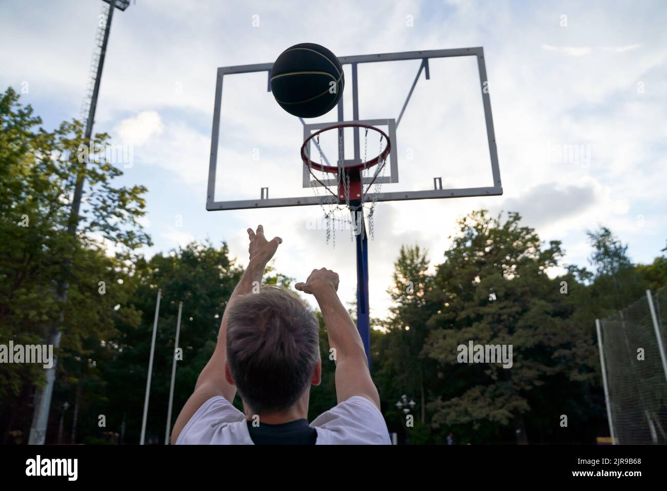 Man is throwing ball to the hoop. Training of basketball on the street ...