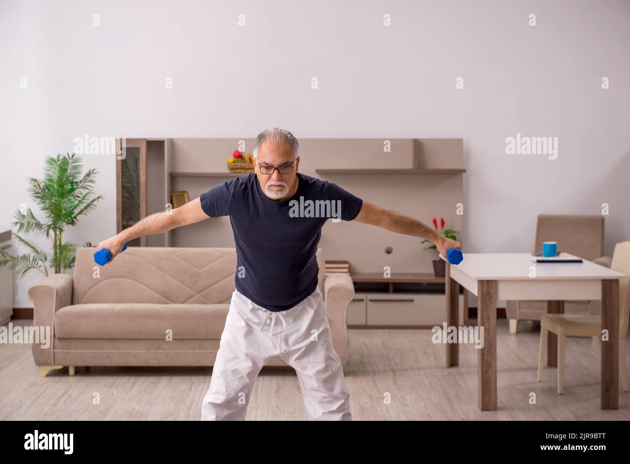 Old man doing sport exercises indoors Stock Photo - Alamy