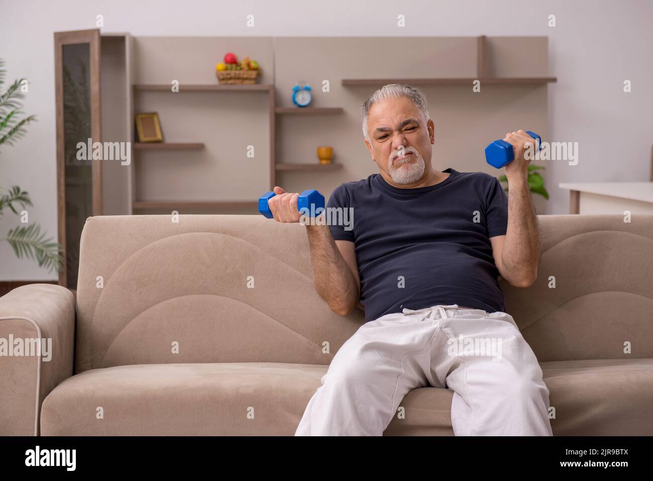Old man doing sport exercises indoors Stock Photo - Alamy