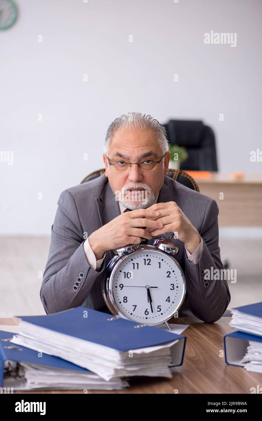 Old male boss in time management concept Stock Photo - Alamy