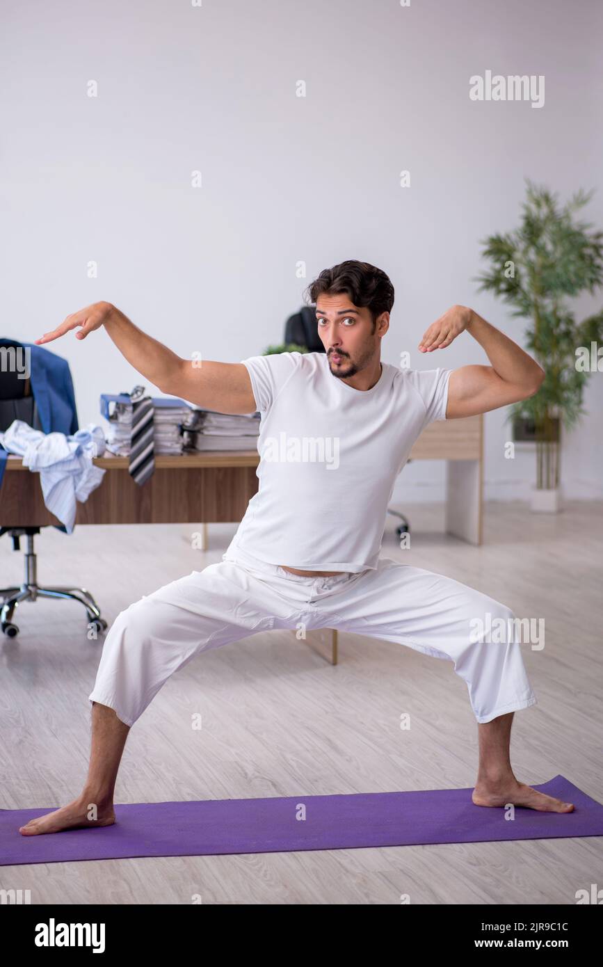 Young businessman employee doing sport exercises at workplace Stock ...