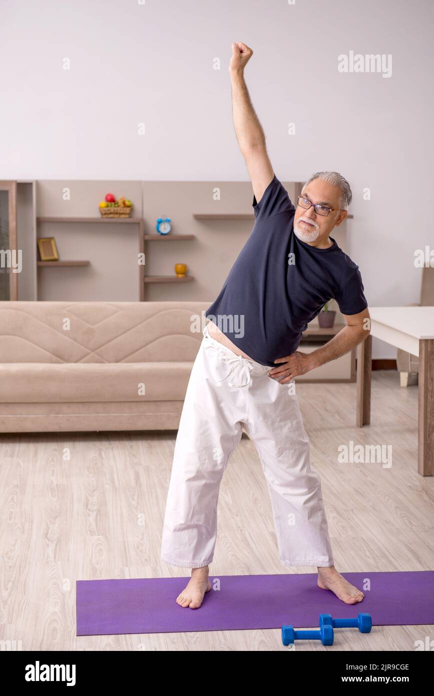 Old man doing sport exercises indoors Stock Photo - Alamy