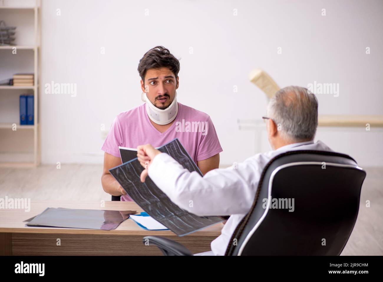 Young neck injured patient visiting old doctor Stock Photo - Alamy
