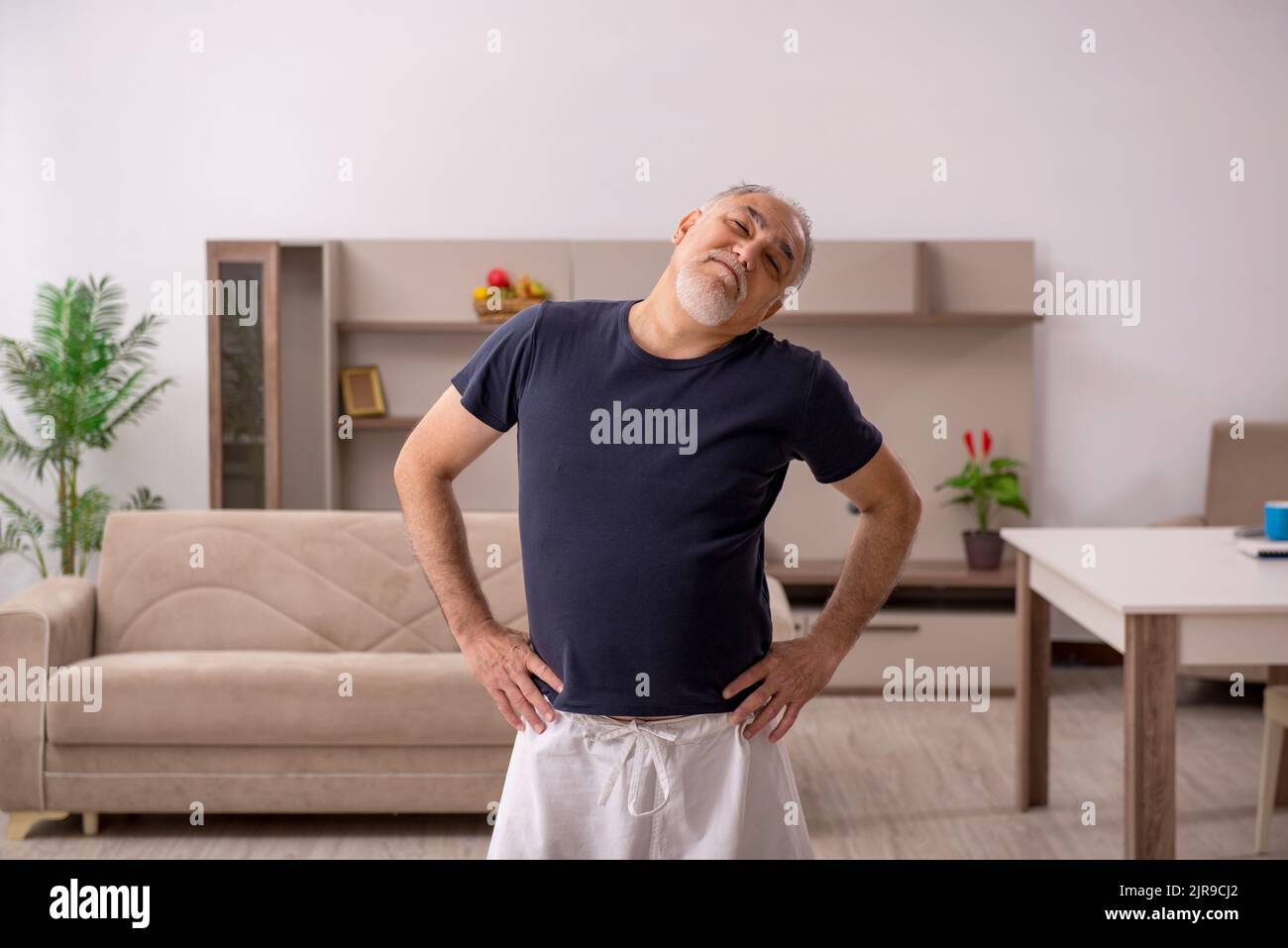 Old man doing sport exercises indoors Stock Photo - Alamy