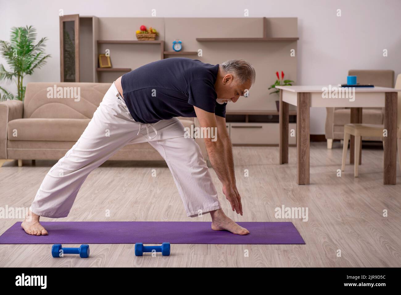 Old man doing sport exercises indoors Stock Photo - Alamy