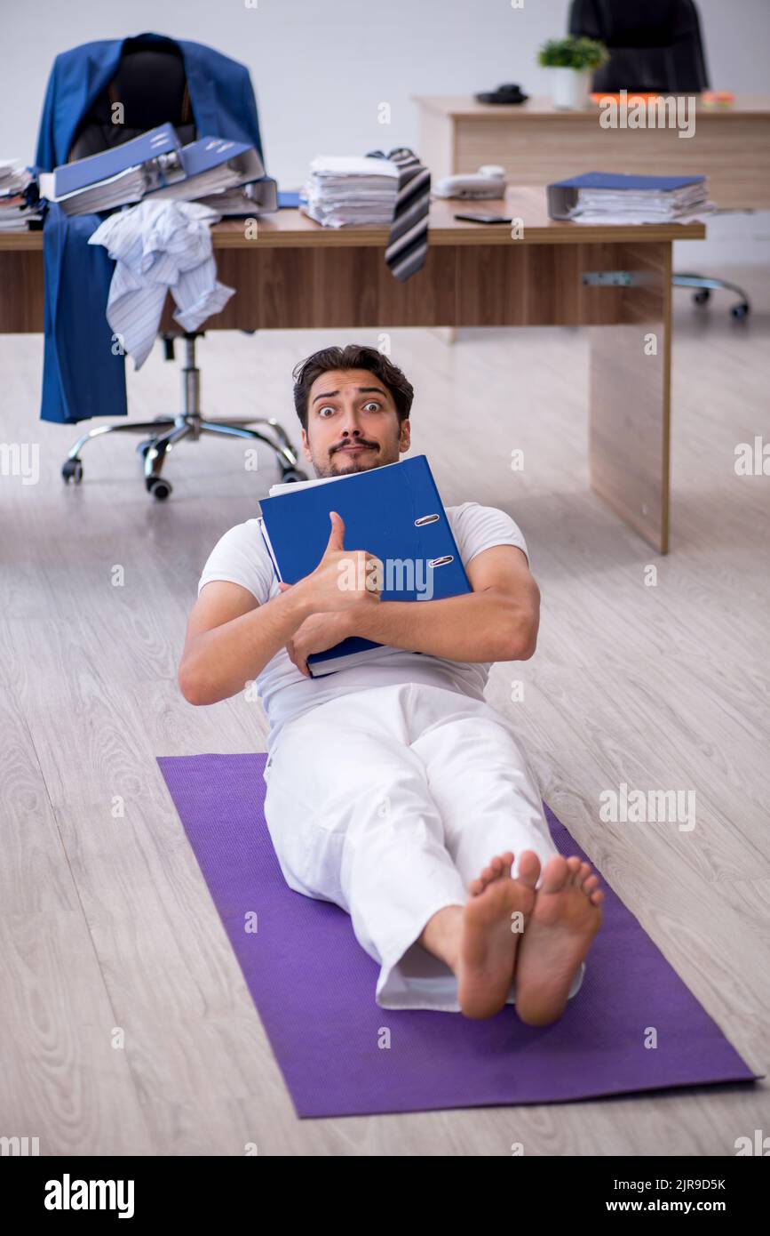 Young businessman employee doing sport exercises at workplace Stock ...