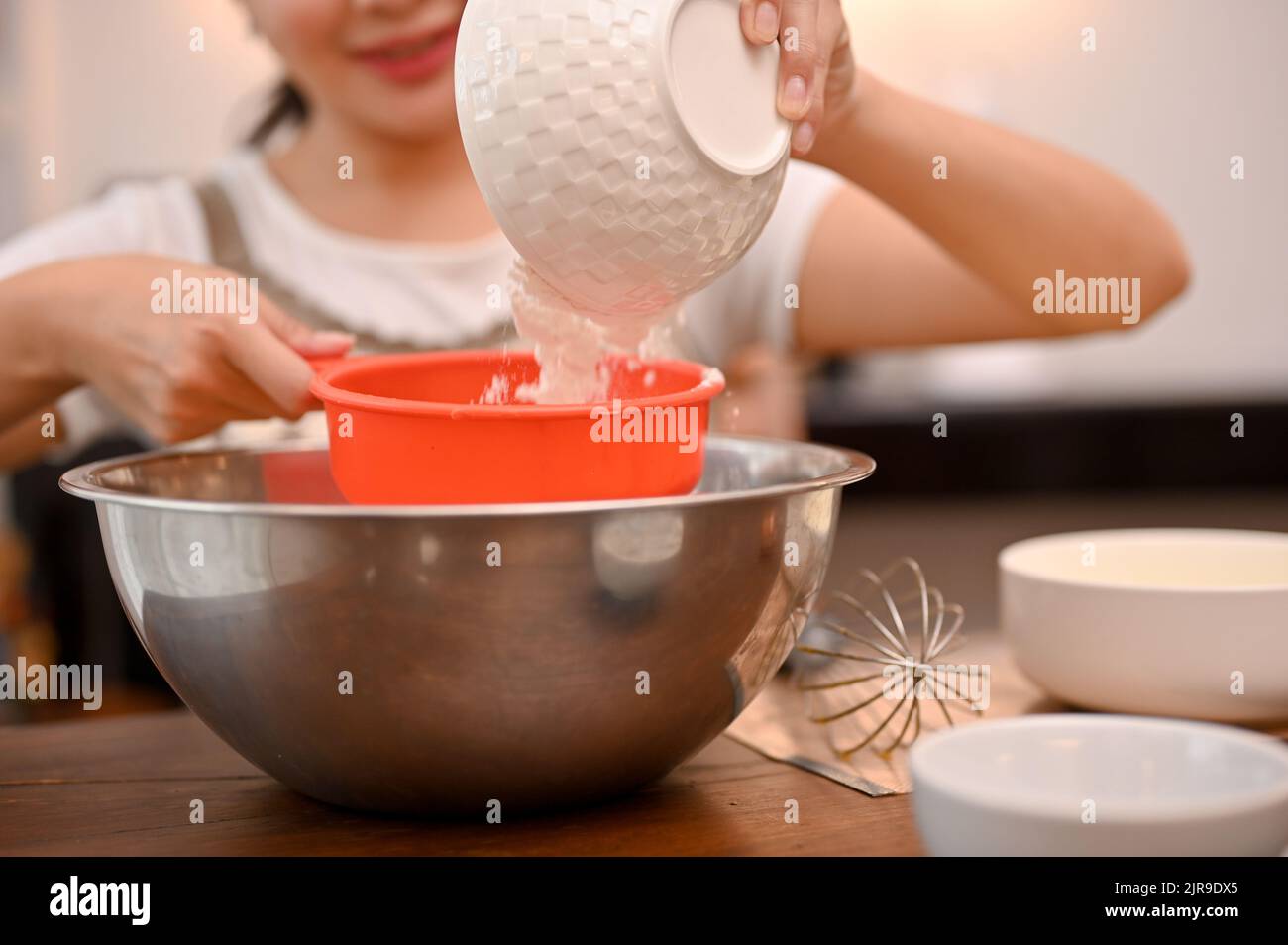 Attractive young Asian female is baking cupcakes in her kitchen ...