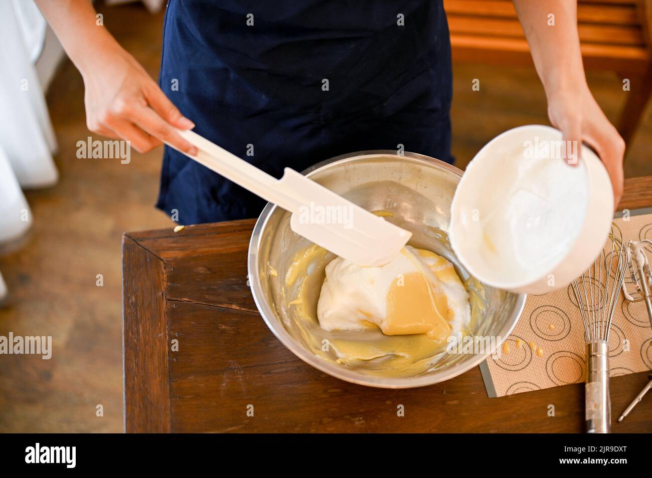 Top view, A female baker adding sugar in her mixing bowl, preparing ...