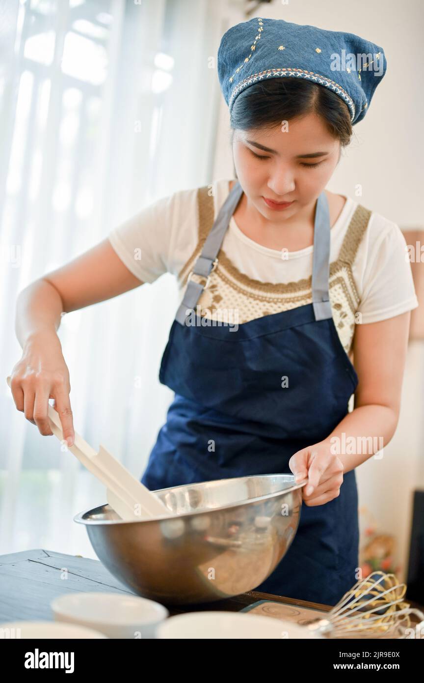 Portrait, Pretty young Asian female baker preparing cupcake flour in ...